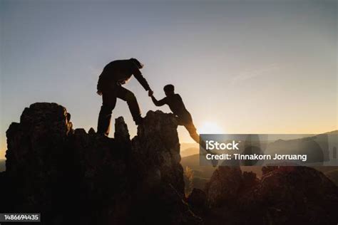 등산 팀 꼭대기에서 서로를 돕는 두 남자 등산객의 팀워크의 실루엣 팀워크 우정 하이킹은 산 일출에서 서로 신뢰 지원 실루엣을 돕습니다 18 19세에 대한 스톡 사진 및 기타