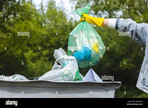 Throwing Garbage Into A Trash Can Close Up Of A Hand Holding A Garbage