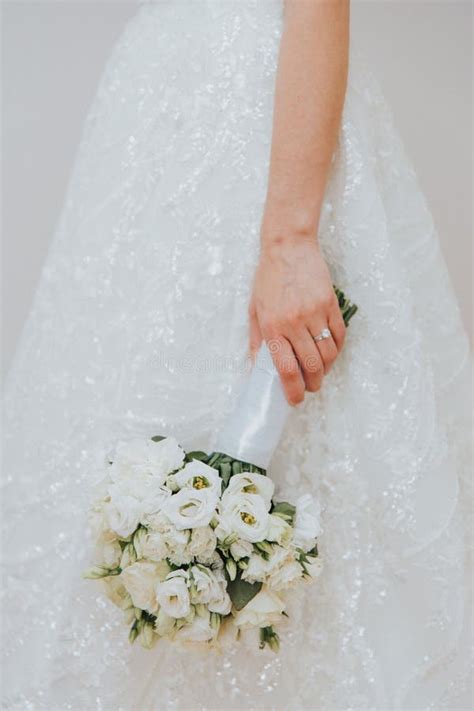 Woman Wearing A White Wedding Dress And Holding A Bouquet Of Flowers