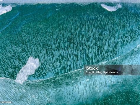 凍った湖に白い泡と亀裂がある冬の氷の自然な質感凍ったバイカル湖の表面の氷と亀裂の抽象的な背景 アイススケート場のストックフォトや画像を多数