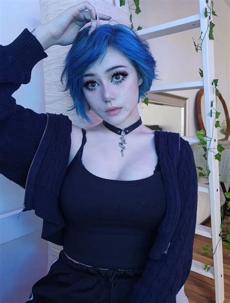 A Woman With Blue Hair Wearing A Choker And Black Top Posing For The Camera