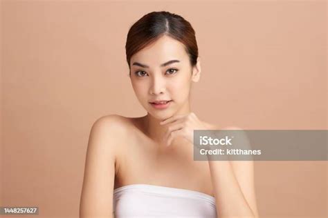 베이지 색 배경에 깨끗한 신선한 피부를 가진 아름다운 젊은 아시아 여성 얼굴 관리 얼굴 치료 화장품 아름다움과 스파 아시아 여성