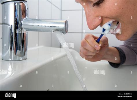 Woman Is Brushing Her Teeth While Water Is Still Running From The Tap