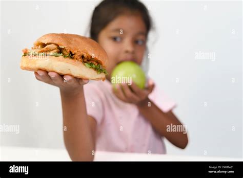 Girl Deciding Between A Juicy Burger And A Fresh Apple Highlighting