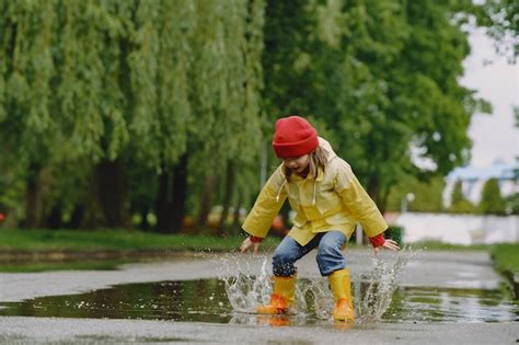 Niño Con Botas De Lluvia Naranja Caminando En Un Charco Foto Premium