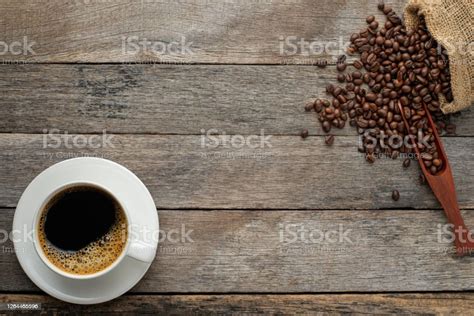 나무 소박한 테이블 배경에 자루 가방에 구운 커피 콩과 흰색 세라믹 컵에 우유 거품 뜨거운 신선한 검은 커피의 상단 보기 복사 공간이 있는 플랫 레이 가방에 대한 스톡 사진