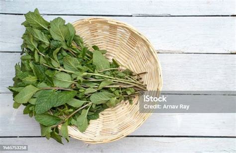 복사 공간이 있는 흰색 나무 배경에 격리된 대나무 바구니에 담긴 신선하고 유기적인 민트 잎 또는 푸디나 잎의 상위 뷰 0명에