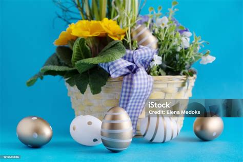 금색 페인트로 칠해진 부활절 달걀은 파란색 배경에 봄 꽃이 있는 고리버들 바구니 앞에 서 있습니다 부활절 카드 봄 방학 꽃 식물에 대한 스톡 사진 및 기타 이미지 Istock