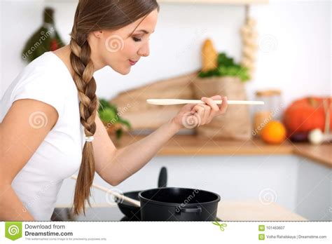 De Jonge Vrouw Kookt In Een Keuken De Huisvrouw Proeft De Soep Door