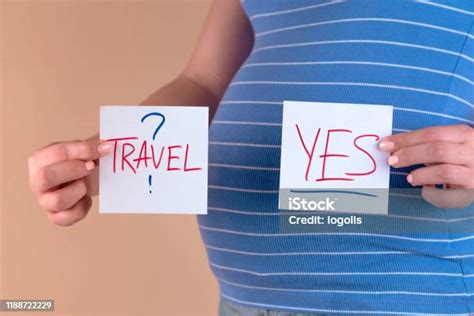 파란색 티셔츠를 입은 임산부의 배를 클로즈업한 모습은 여행용 여행과 예라는 문구가 적어 손안에 있는 전단지입니다 임신 중 여행