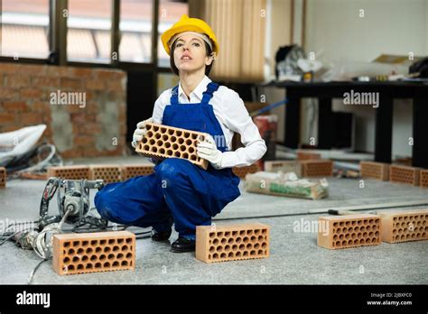 Female Builder In Safety Hard Hat Preparing Bricks For Erection Of Partition Wall Stock Photo