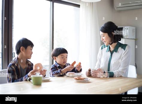 Brothers Eating Doughnuts As A Snack And Their Mother Watching Them