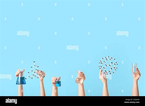 Female Hands Holding Molecular Models And Filled Flasks With Measuring Cup On Blue Background