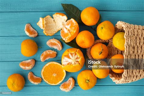 오렌지 육즙 귤 조각과 껍질을 벗긴 만다린이 나무 청록색 배경에 흩어져 있습니다 플랫 레이 공간을 복사합니다 고리 버들 바구니에 신선한 여름 비타민이 풍부한 과일 비타민에