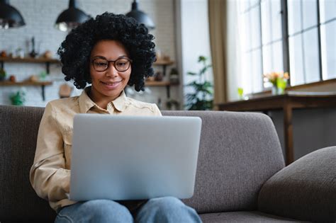 집중 미소 아프리카 여자는 소파에 앉아서 노트북에서 원격으로 인터넷 검색 집에서 컴퓨터 복사 빈 공간을 사용하는 여성 프리랜서 사업가 25 29세에 대한 스톡 사진 및 기타