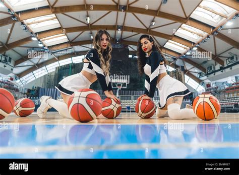 Two Cheerleaders Wearing White And Navy Blue Costumes Posing With