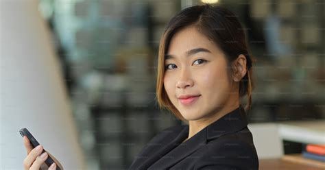 검은 양복을 입은 젊은 사업가의 초상화의 측면 모습은 스마트폰을 들고 카메라를 바라보며 웃고 있다 사진 Unsplash의 앉아 이미지