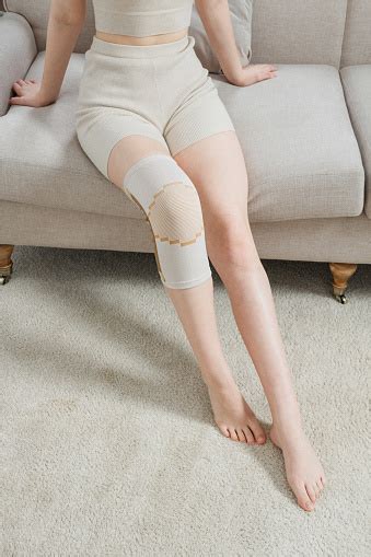 여자 다리에 무릎 받침 보조기 집 안에있는 보조기에있는 소녀 무릎 고정 부상 및 통증을위한 정형 외과 해부학 적 중괄호 무릎