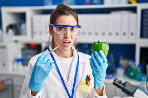 Young Hispanic Woman Working At Scientist Laboratory With Vegetables