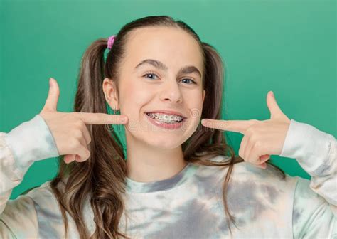 Portrait Of Smiling Beautiful Teenage Girl With Braces Pointing