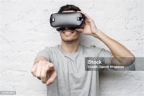 잘생긴 백인 젊은이 3d 안경을 쓰고 뭔가와 상호 작용 하는 경우에 그의 손가락을 가리키는 비디오 게임을 재생 하는 동안 발생