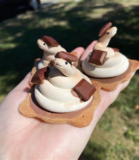 Two Small Figurines Sitting On Top Of A Piece Of Bread In The Palm Of