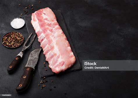 검은 돌 배경에 보드와 빈티지 고기 포크와 칼을도 마에 신선한 원료 돼지 갈비뼈 소금 후추 텍스트를 위한 공간 고기에 대한 스톡
