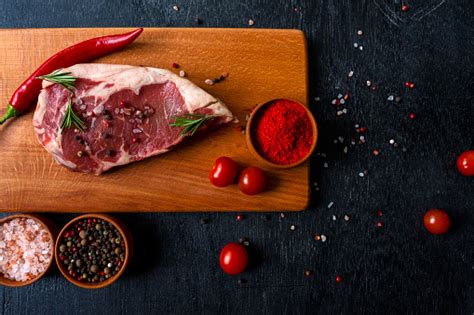 나무 테이블에 나무 도마에 리비아이 쇠고기 고기의 원시 조각은 고추 후추 파프리카와 히말라야 소금으로 장식 토마토 누적 신선한