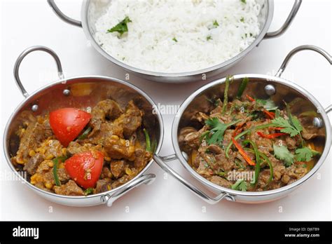 A Bowl Of Spiced Lamb Curry With Coriander Leaves And Chillies Next To