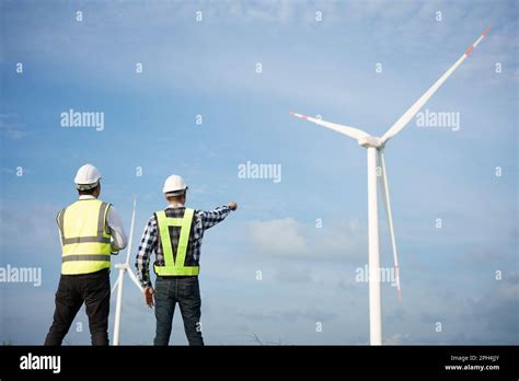 Two Asian Engineers Discussing And Checking Turbines On Wind Turbine Farm Renewable Energy