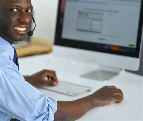 African American Businessman On Headset Working On His Laptop Stock