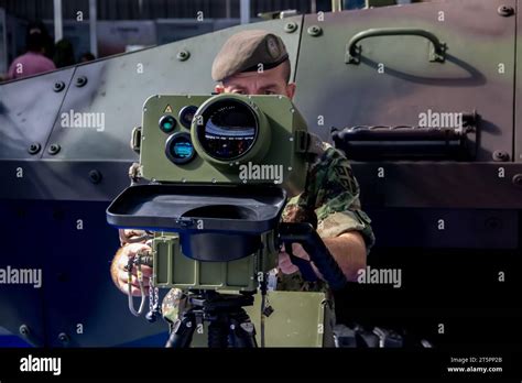 Soldier In Camouflaged Uniform Armed With Military Equipment Next To
