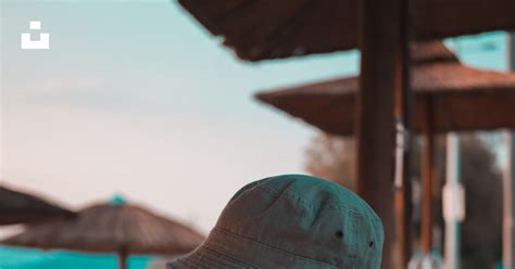 낮 동안 의자에 앉아 파란색 모자를 쓰고 파란색과 빨간색 꽃 탱크 탑을 입은 여자 사진 Unsplash의 무료 바닷가 이미지