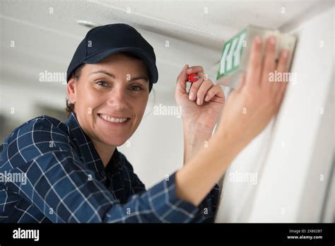 Female Contractor Installing Illuminated Exit Sign Stock Photo Alamy