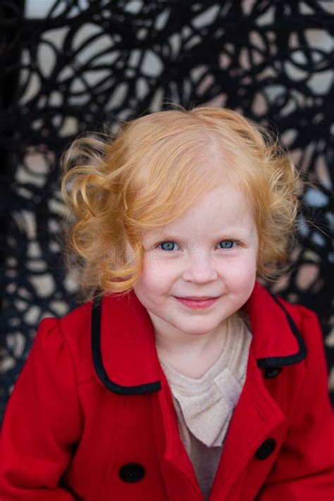 Retrato De Uma Menina Bonita Com Cabelo Vermelho Em Um Revestimento Vermelho Imagem De Stock