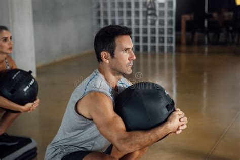 Sporty Man Doing Squats With Fitness Ball In The Gym Stock Image