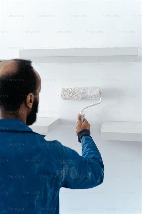 Un Homme Peignant Un Mur Avec De La Peinture Blanche Photo Diy Photo