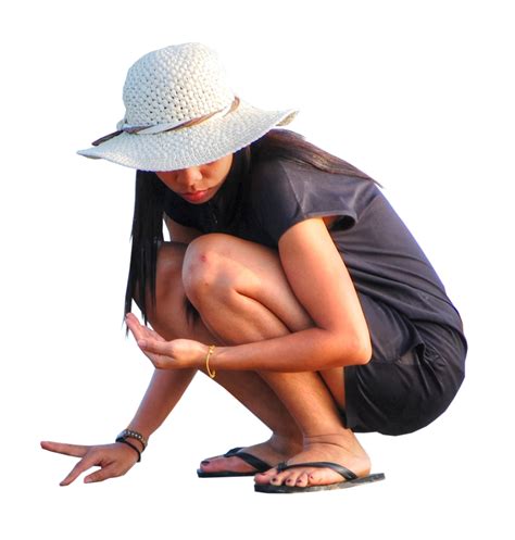 A Woman Kneeling Down With Her Hands On Her Knees And Wearing A Hat
