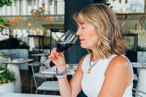 레드 와인 한 잔의 풍부한 향을 음미하는 전문 소믈리에가 세련되고 현대적인 레스토랑에서 세련된 분위기를 즐기며 복잡한 꽃다발에 잠기십시오 50 59세에 대한 스톡 사진 및