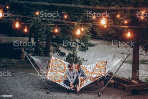 세련 된 Hipster 몇 껴 안고와 여름 공원 저녁에 복고풍 조명 아래 해먹에서 휴식 사람이 포옹 여자와 숲에서 휴식입니다