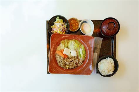 일본 음식 스타일 돼지 고기 스키야키 세트에 쌀 흰 양배추 당근 두부 야채 샐러드 삶은 계란 김치와 함께 타일 접시에 넣고 흰색 테이블에 놓습니다 건강한 생활방식에 대한