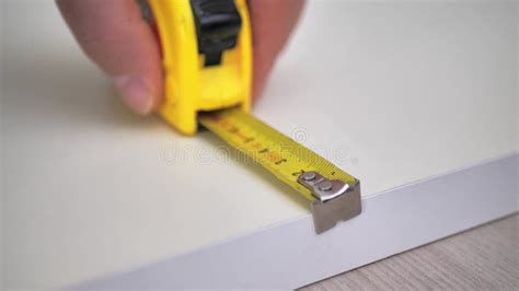 Female Hand Presses Button Of An Orange Metallic Tape Measure With A