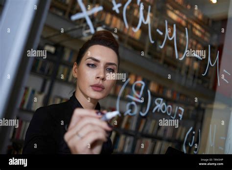 Female Computer Coder Writing Down A Complex Code On A Window At Her