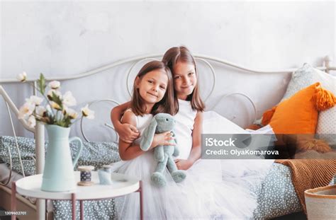 Dua Gadis Cantik Berpelukan Di Tempat Tidur Adikadik Duduk Di Ruangan