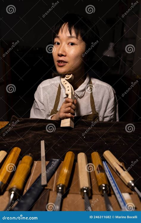Young Chinese Woman Violin Maker Showing The Neck Of The Violins Under