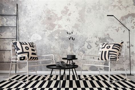 흰색 의자 둥근 커피 테이블 검은 사다리 무늬가 있는 베개 장식 및 카펫이 있는 로프트 산업 아파트의 인테리어 디자인 회색 콘크리트 벽 가정 장식 템플렛 0명에 대한 스톡