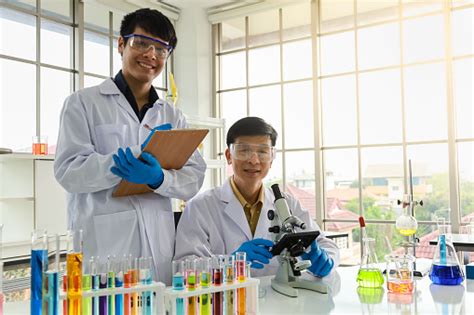작업 실험실에서 현미경과 연구를 사용하여 일하는 두 명의 아시아 전문 수석 및 젊은 의사 과학자의 초상화 과학 및 헬스케어 개념