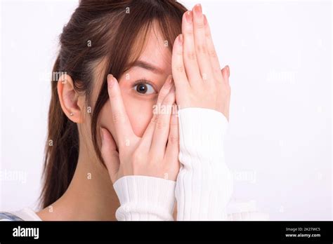 Young Woman Covering Face With Hands And Peeping Through Her Fingers At
