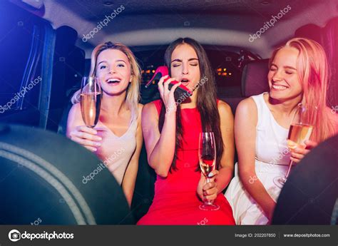 Drunk Girls Are Sitting In Car And Drinking Champagne Brunette Is