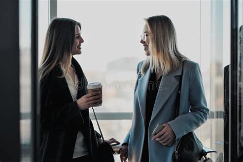 Two Beautiful Girls A Blonde And A Brunette Are Wearing A Coat In A